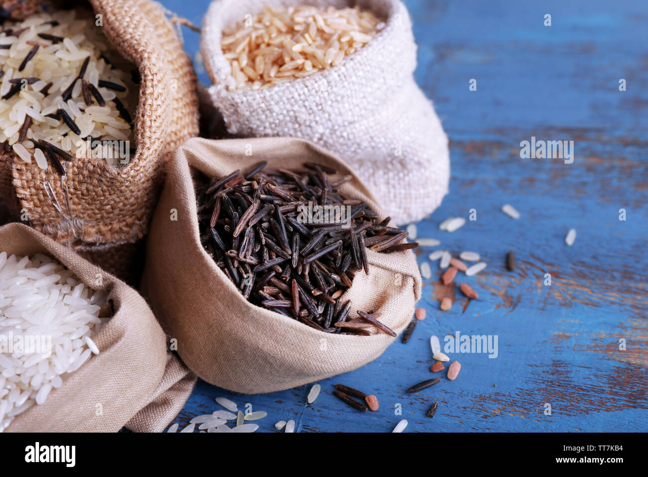 Different types of rice in sacks on wooden background Stock Photo - Alamy