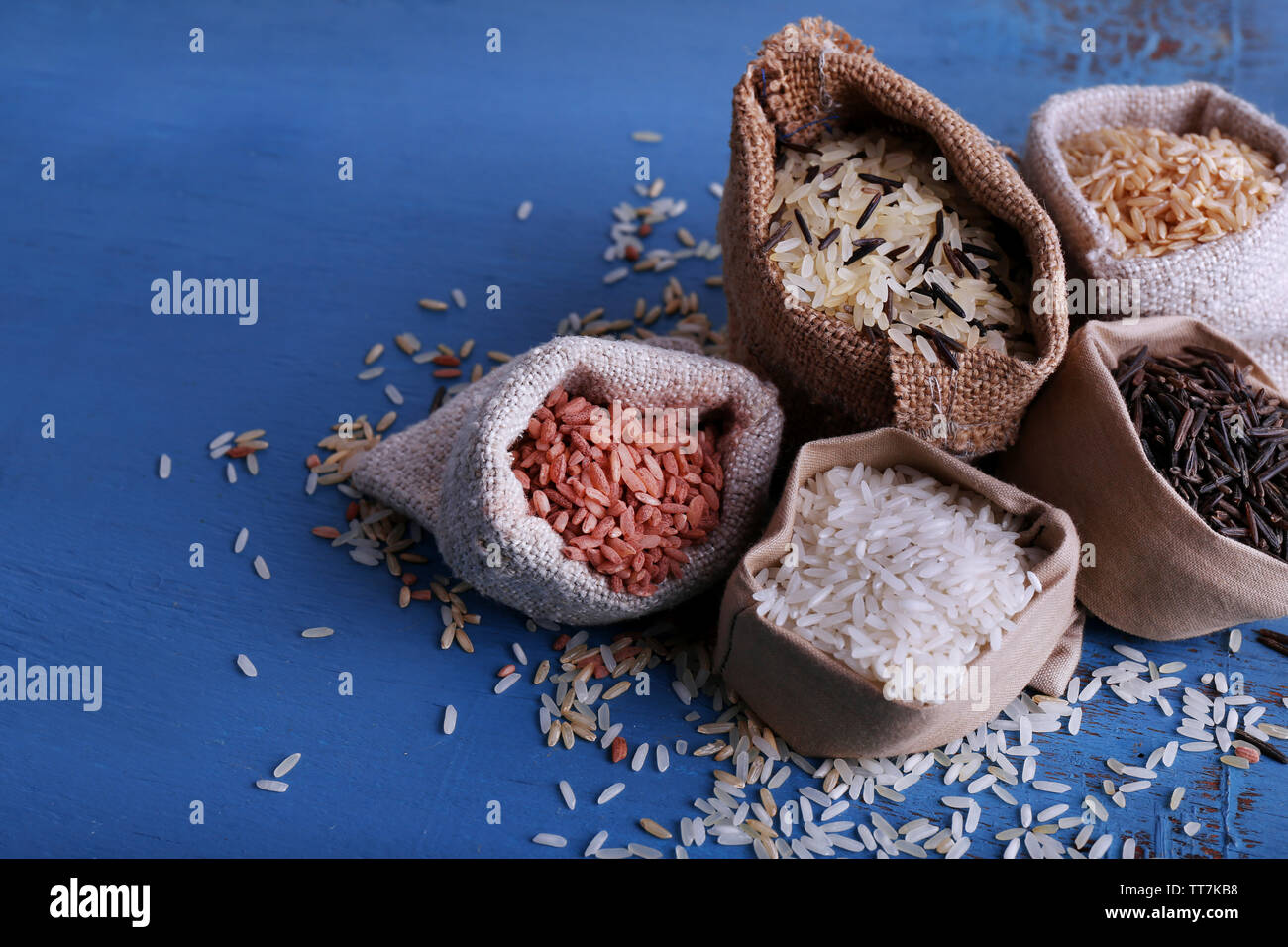 Different types of rice in sacks on wooden background Stock Photo - Alamy