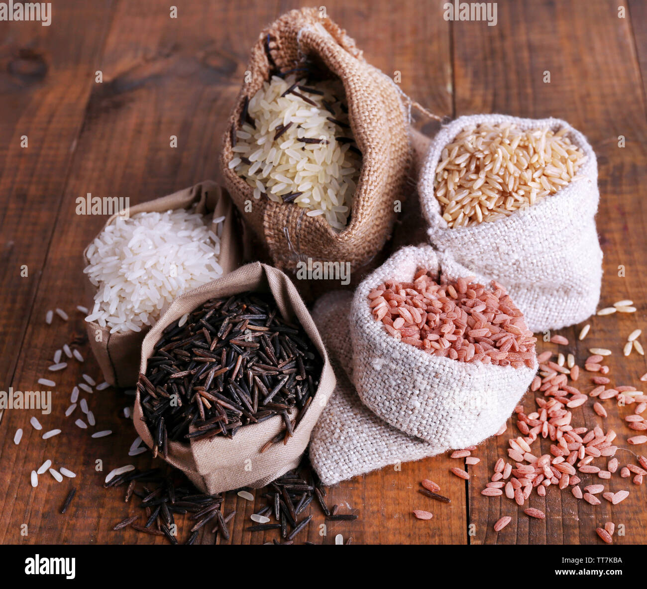 Different types of rice in sacks on wooden background Stock Photo - Alamy