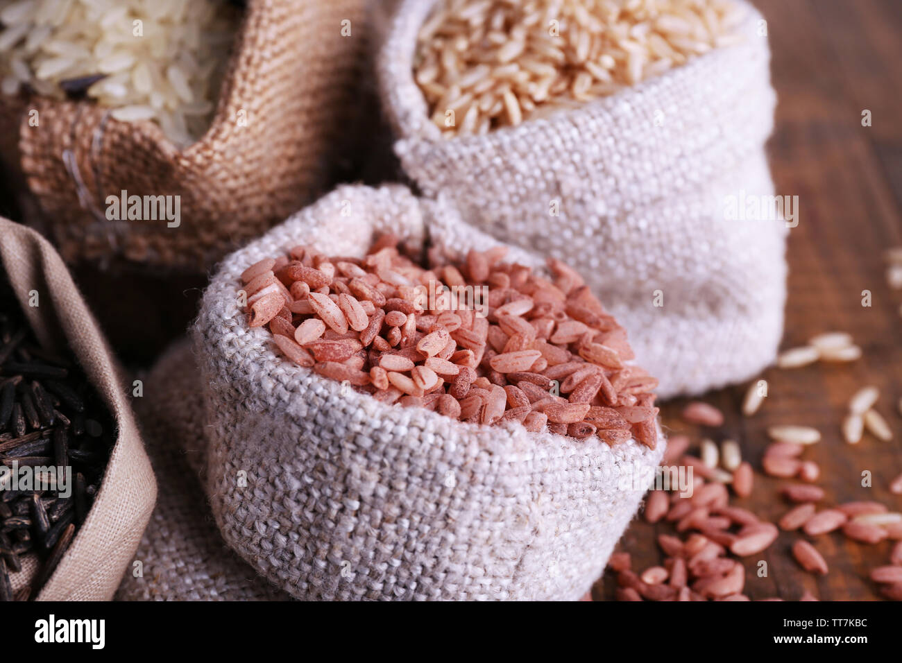 Different types of rice in sacks on wooden background Stock Photo - Alamy