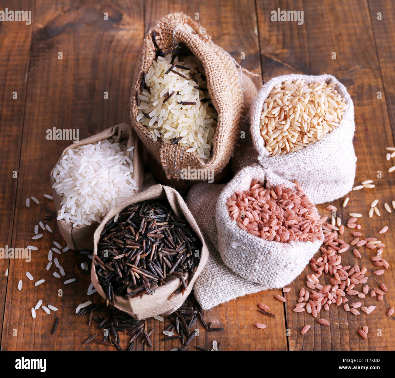 Different types of rice in sacks on wooden background Stock Photo - Alamy