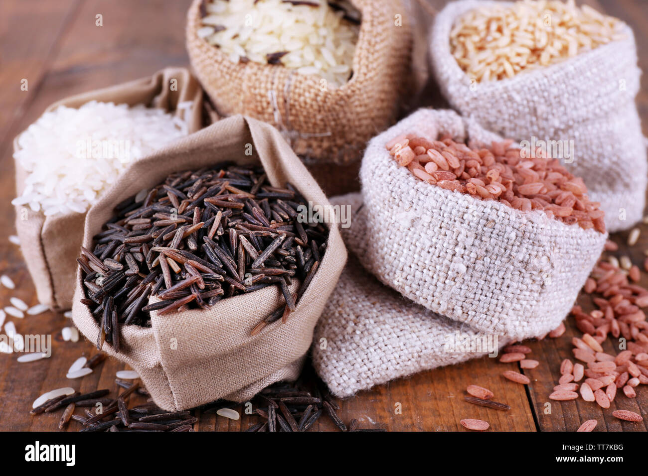 Different types of rice in sacks on wooden background Stock Photo - Alamy