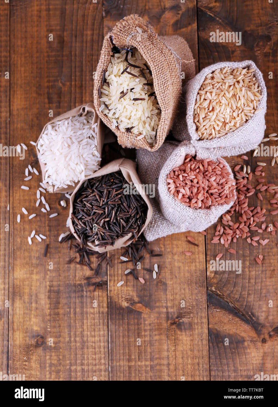 Different types of rice in sacks on wooden background Stock Photo - Alamy
