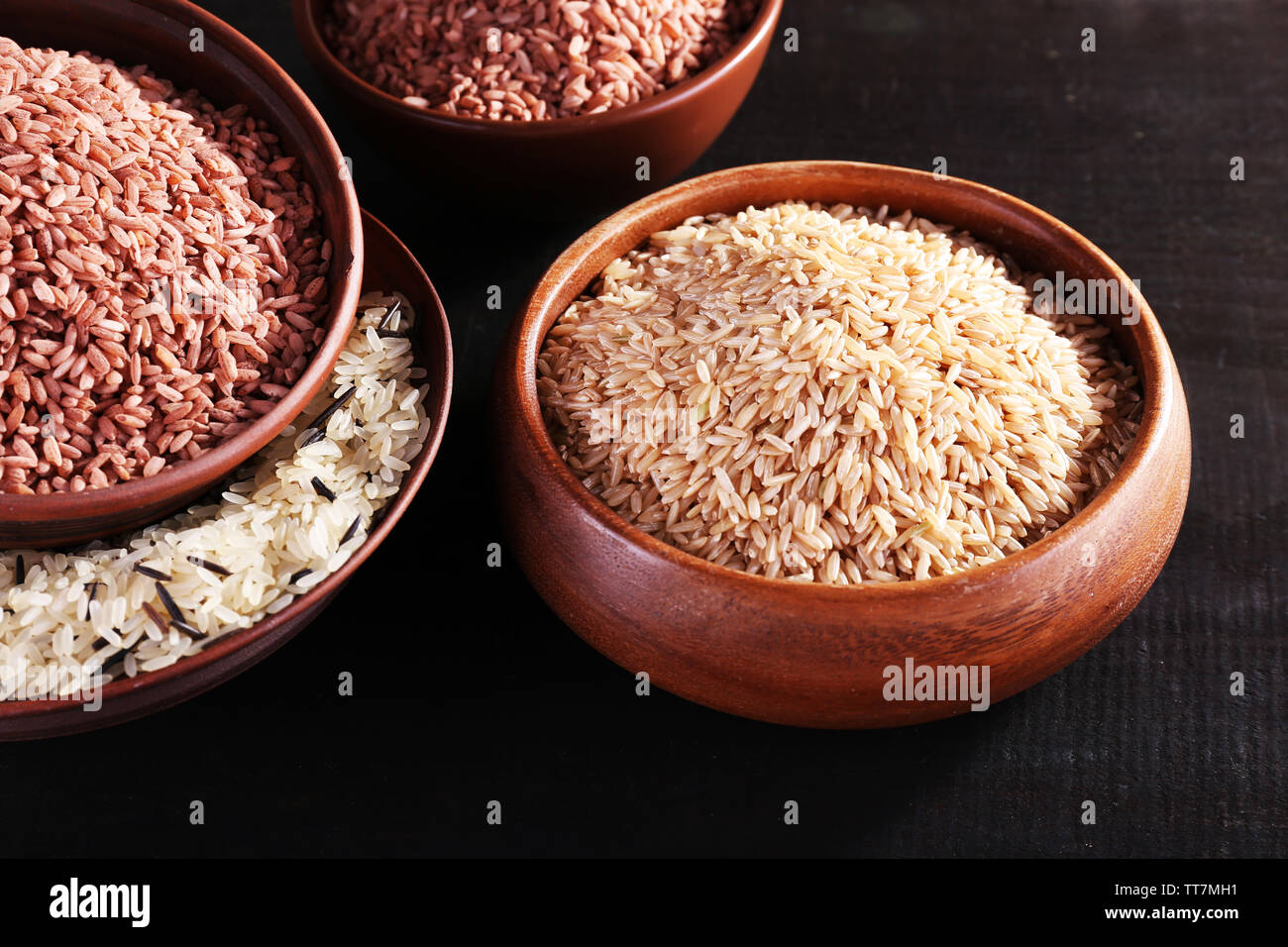 Different kinds of rice in bowls on wooden background Stock Photo - Alamy