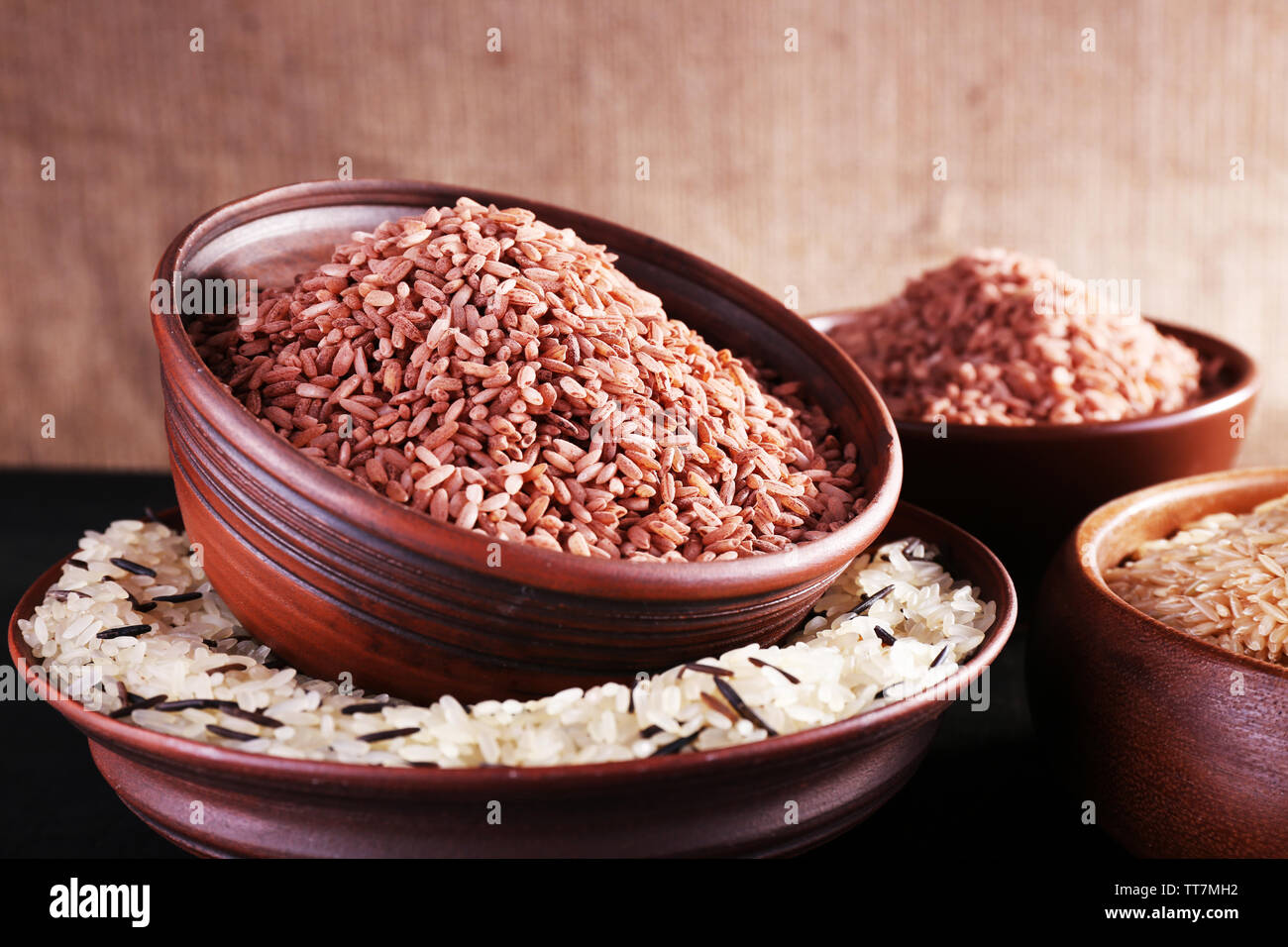 Different kinds of rice in bowls on table on sackcloth background Stock ...
