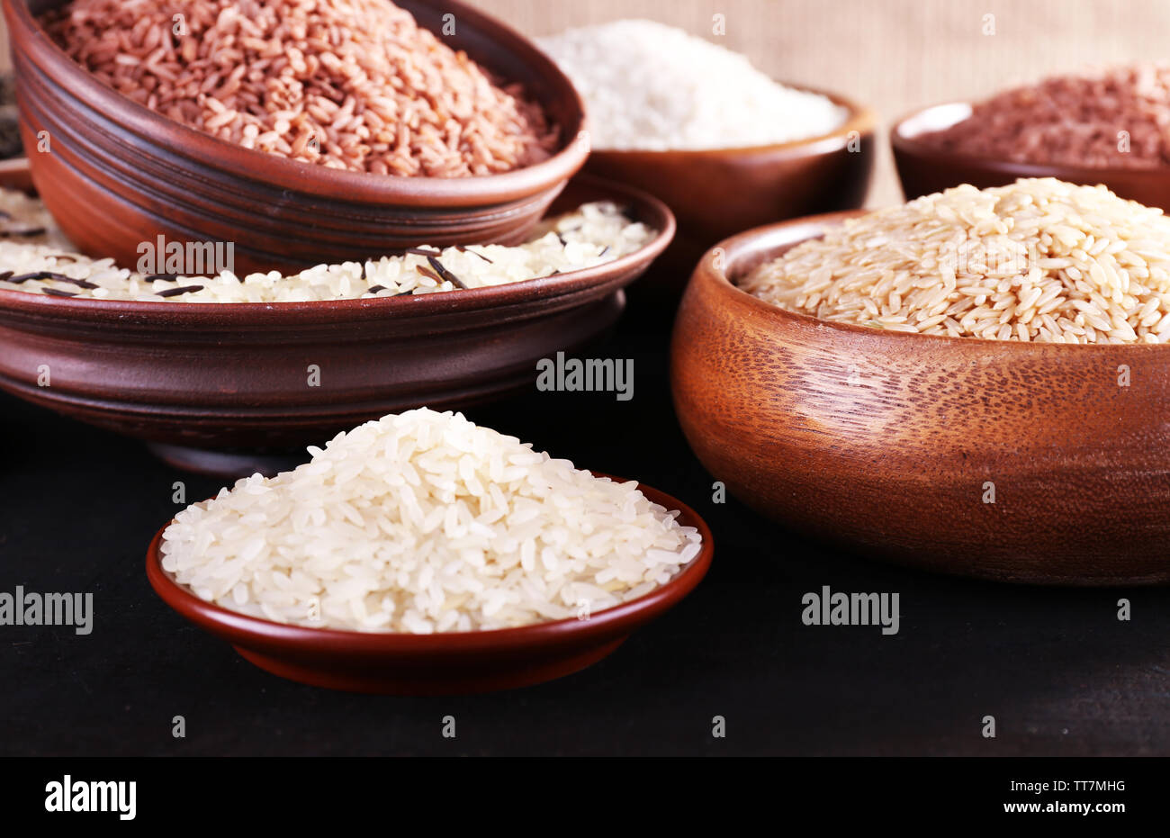 Different kinds of rice in bowls on wooden background Stock Photo - Alamy