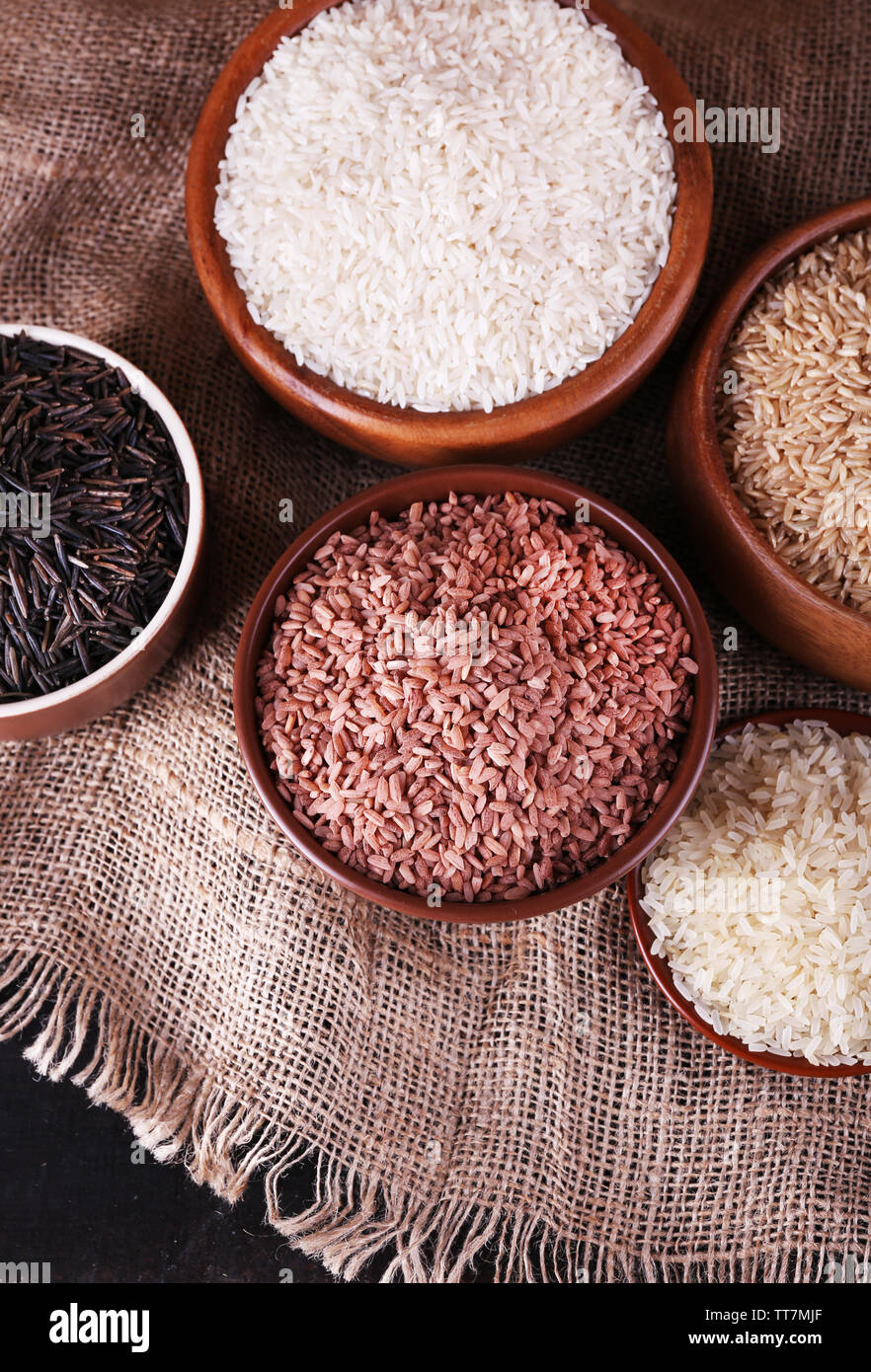Different kinds of rice in bowls on sackcloth background Stock Photo ...