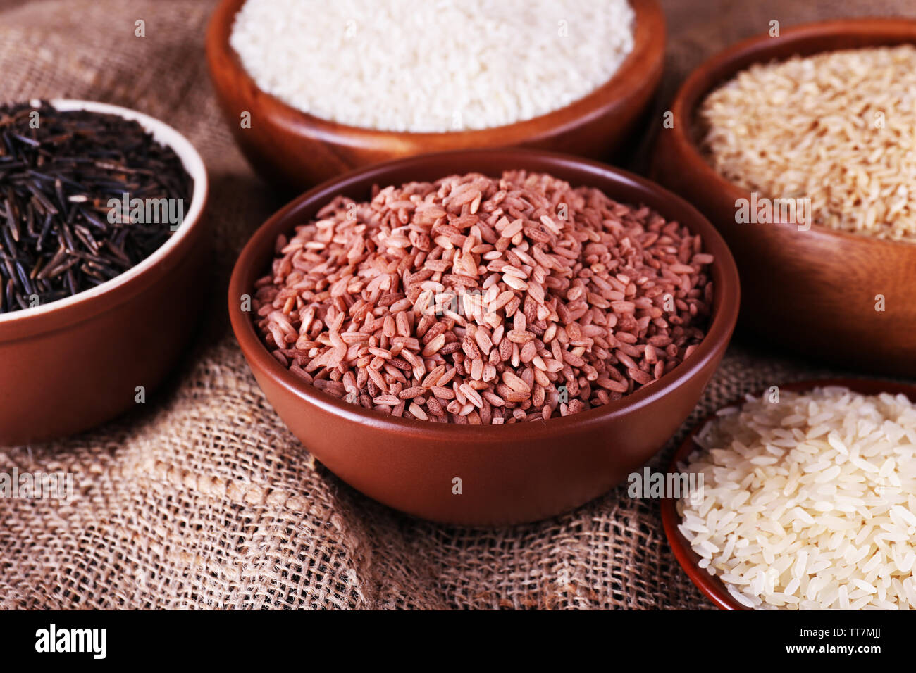 Different kinds of rice in bowls on sackcloth background Stock Photo ...