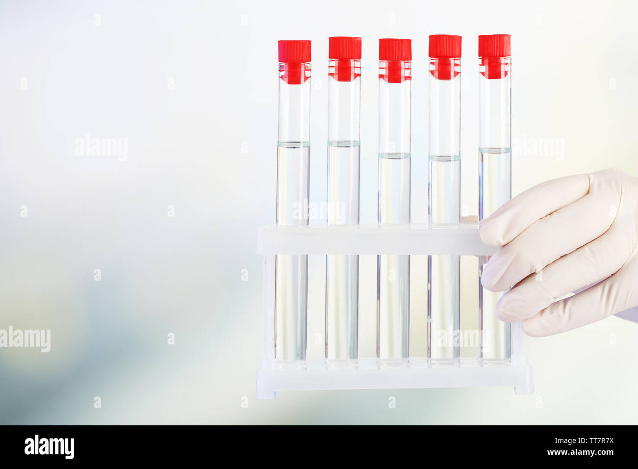 Hand holding test tubes on light background Stock Photo - Alamy