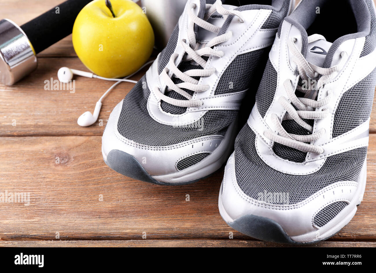 Sports shoes with dumbbell and headphones on wooden background Stock ...