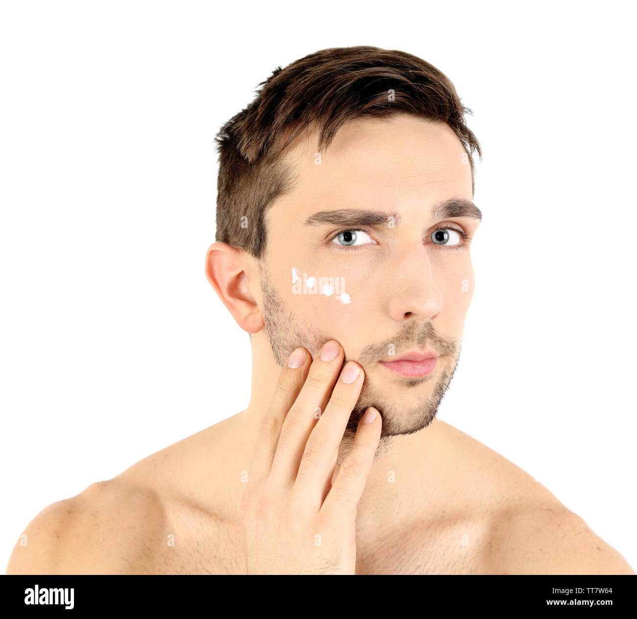 Handsome young man applying cream lotion on face isolated on white ...