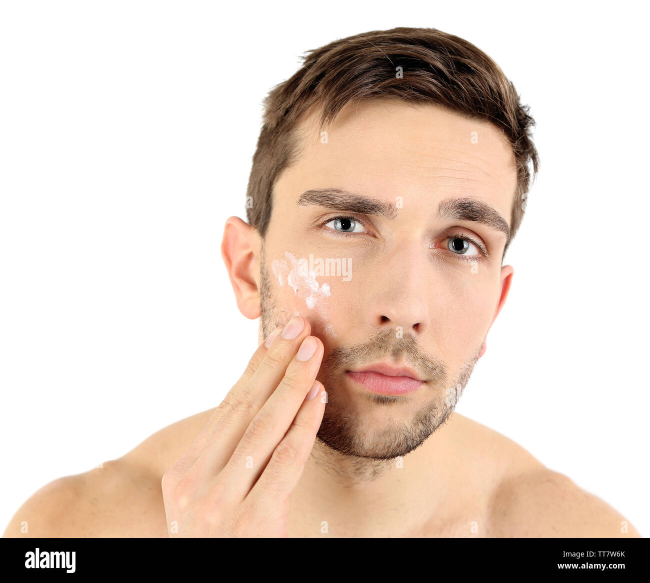 Handsome young man applying cream lotion on face isolated on white ...