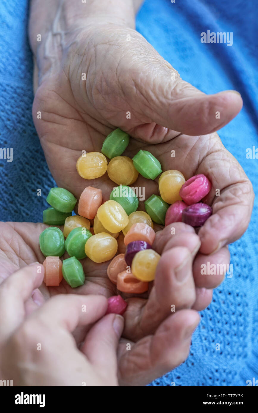 A young hand picks a hard candy from palm of a senior person Stock ...