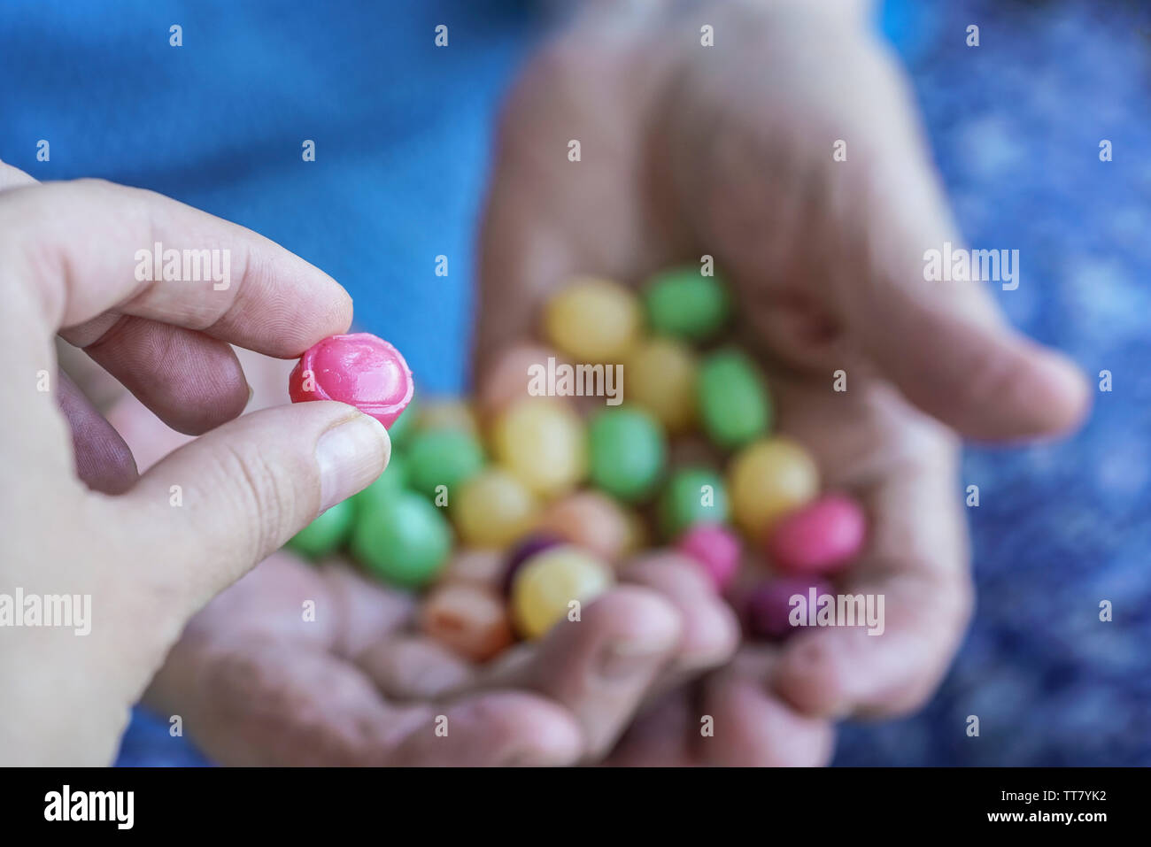 A young hand picks a hard candy from palm of a senior person Stock ...