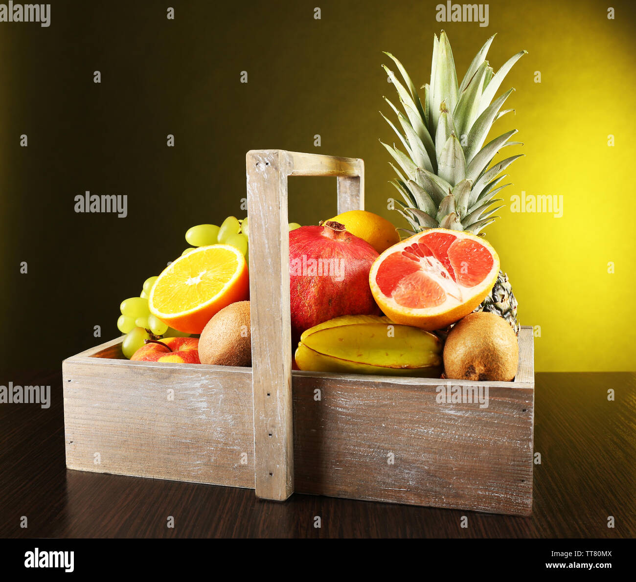 Assortment of fruits in box on dark yellow background Stock Photo - Alamy
