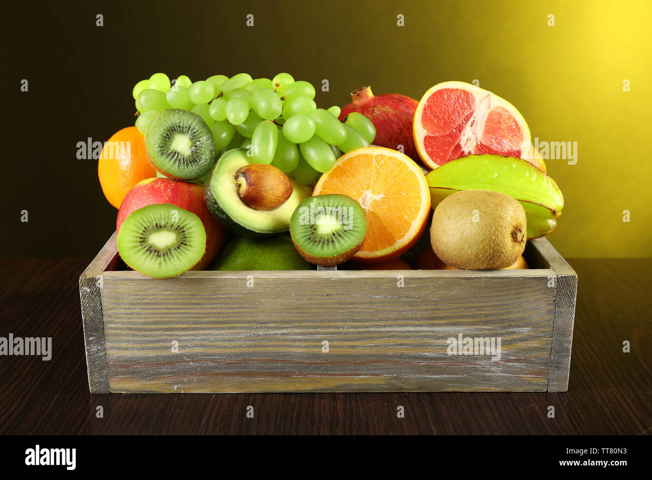 Assortment of fruits in box on dark yellow background Stock Photo - Alamy