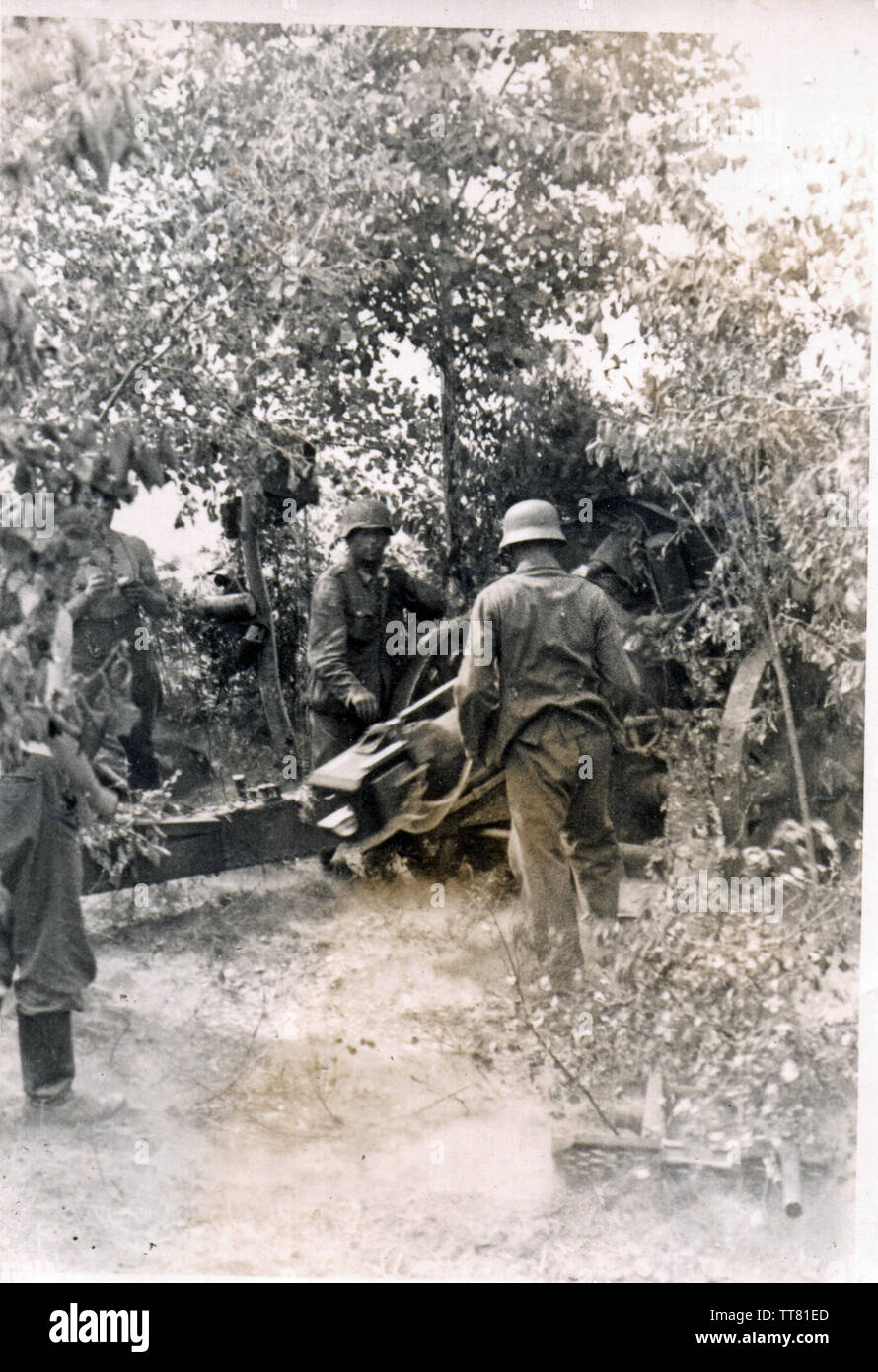 German Soldiers fire their Field Howitzer from a treeline on the ...