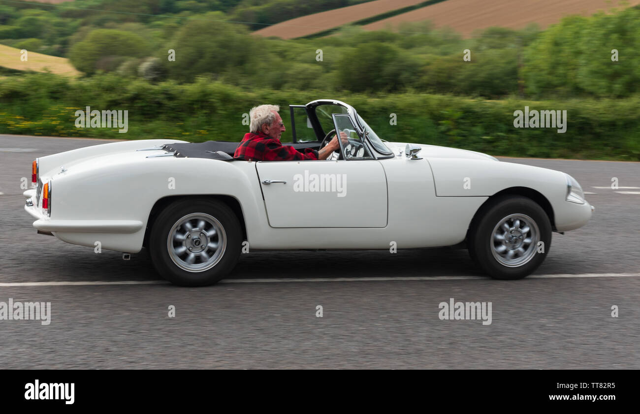 Open top vintage sports car being driven by mature gentleman through ...