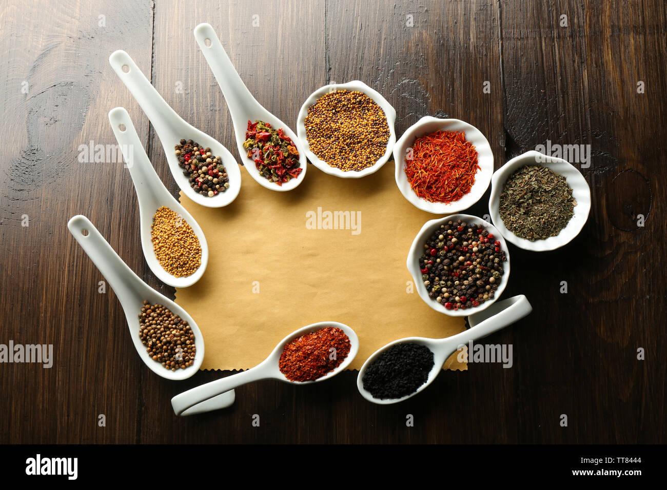 Different kinds of spices in bowls and spoons on blank paper sheet on ...