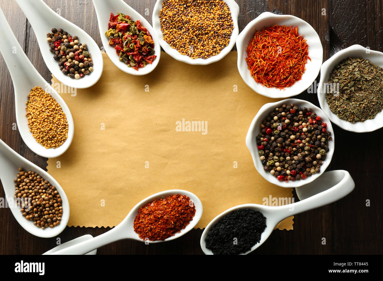 Different kinds of spices in bowls and spoons on blank paper sheet on ...