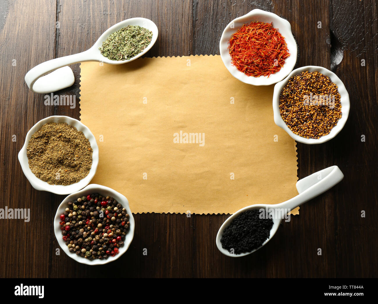 Different kinds of spices in bowls and spoons on blank paper sheet on ...