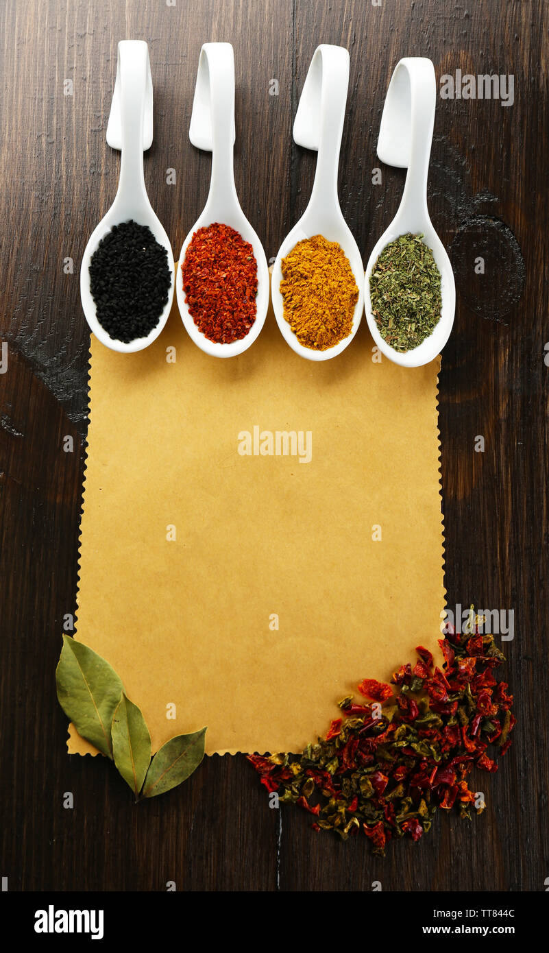 Different kinds of spices in ceramics spoons on blank paper sheet on ...