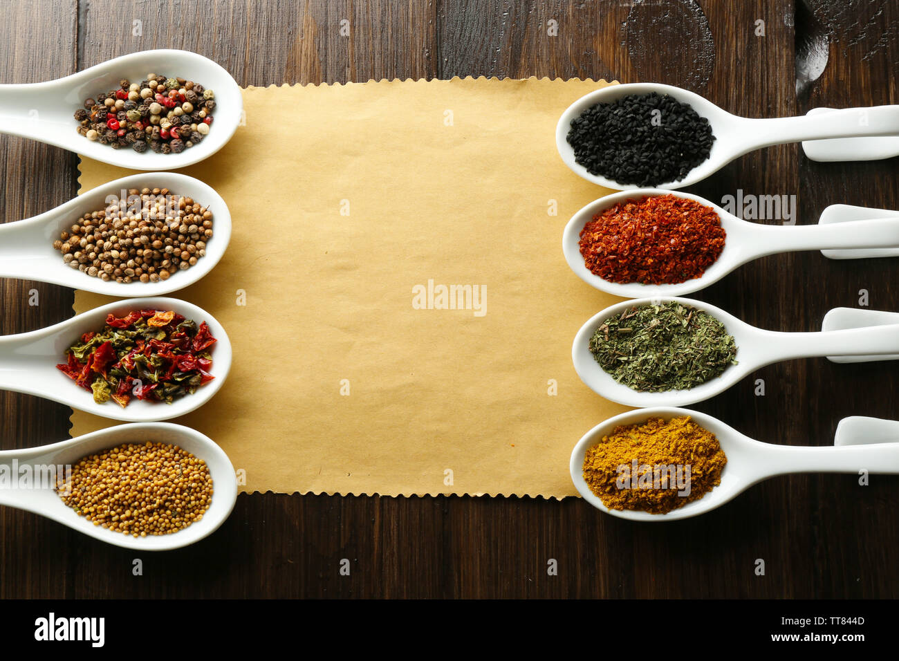 Different kinds of spices in ceramics spoons on blank paper sheet on ...
