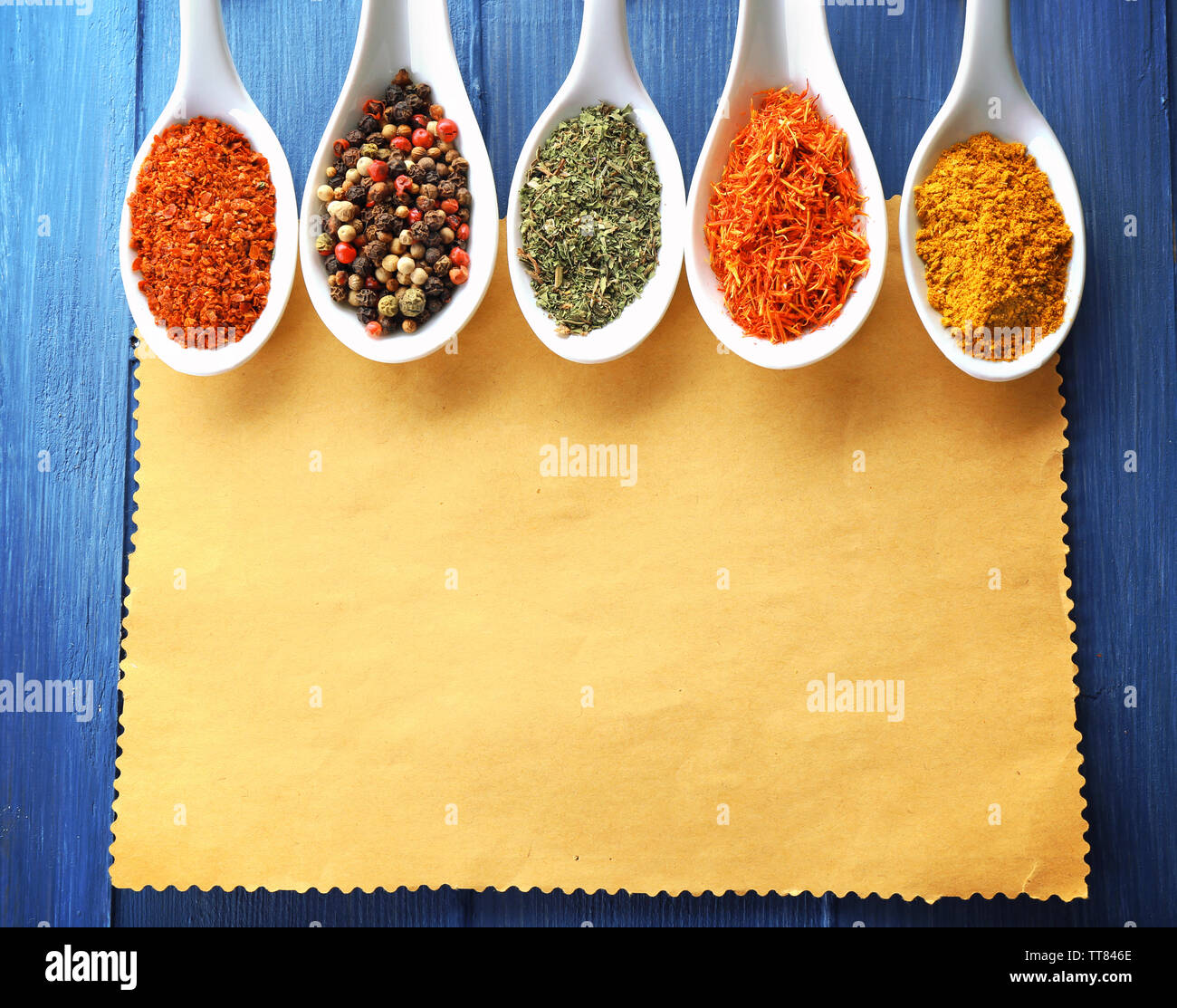 Different kinds of spices in ceramics spoons on blank paper sheet on ...