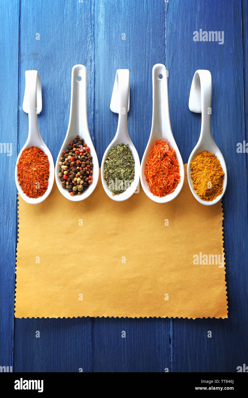 Different kinds of spices in ceramics spoons on blank paper sheet on ...