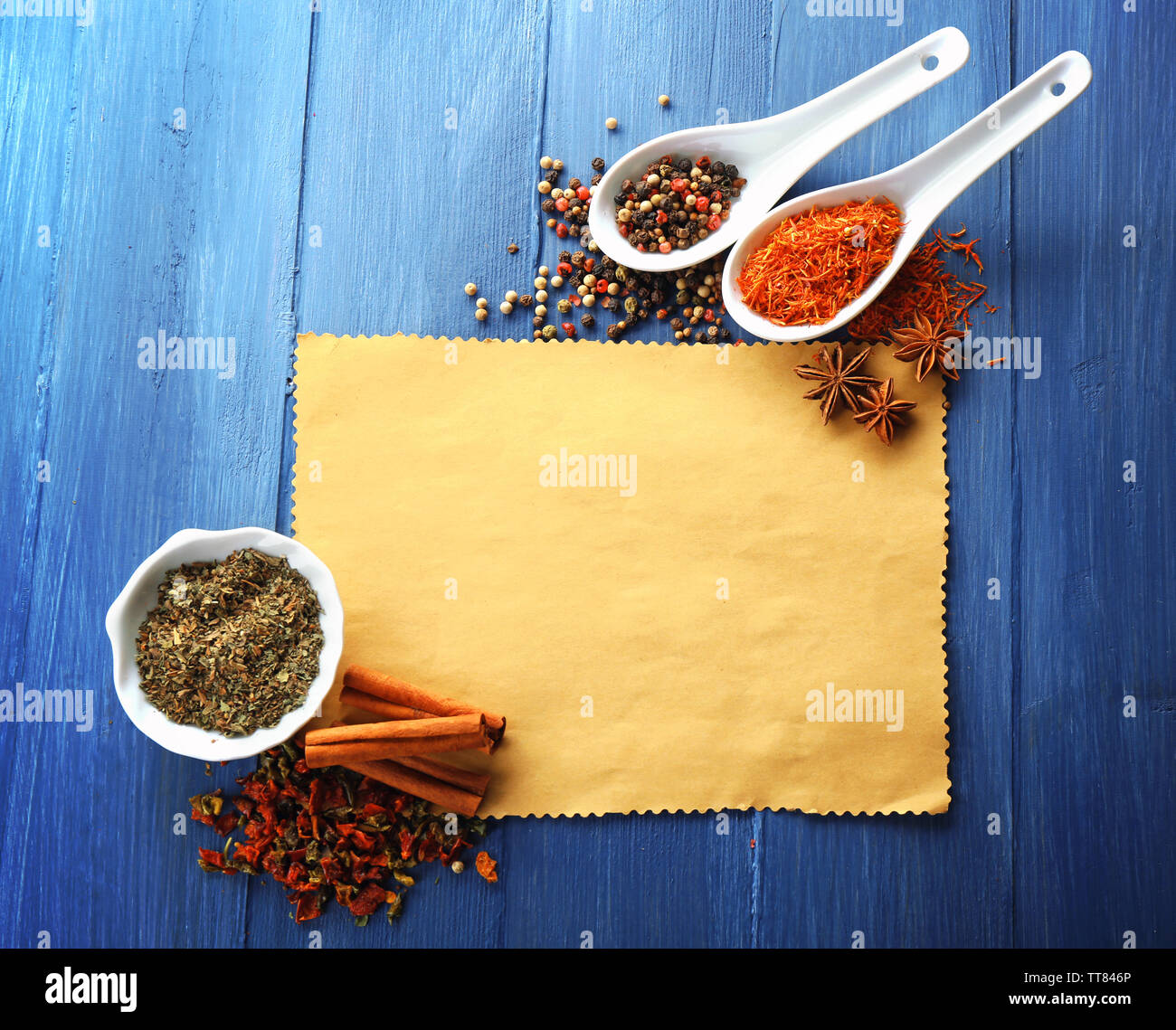 Different kinds of spices on blank paper sheet on wooden background ...