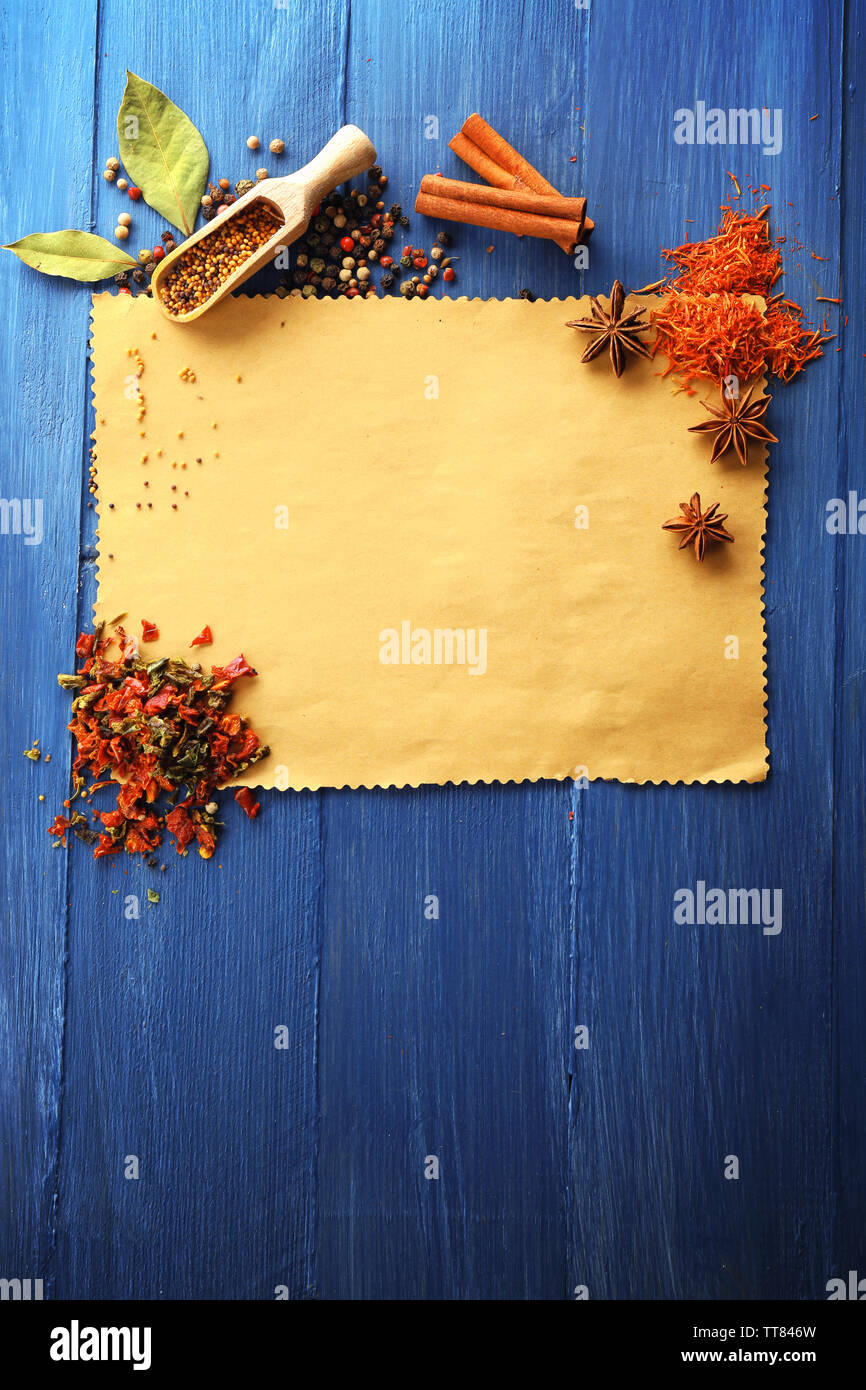 Different kinds of spices on blank paper sheet on wooden background ...