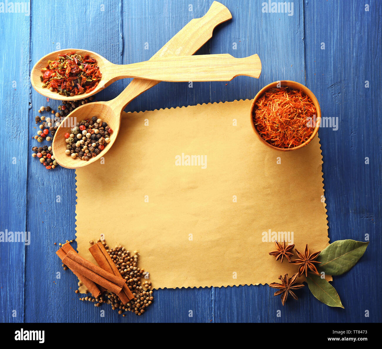 Different kinds of spices on blank paper sheet on wooden background ...