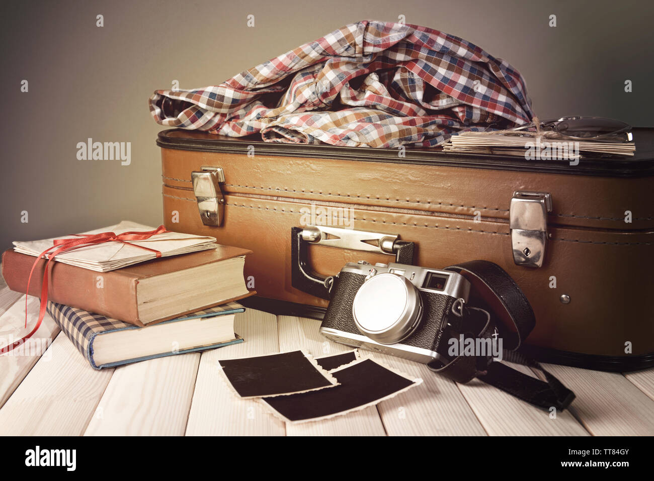 Vintage suitcase with clothes and books on table on dark background ...