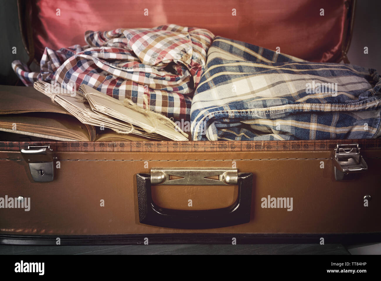 Vintage suitcase open with clothes and books close up Stock Photo - Alamy