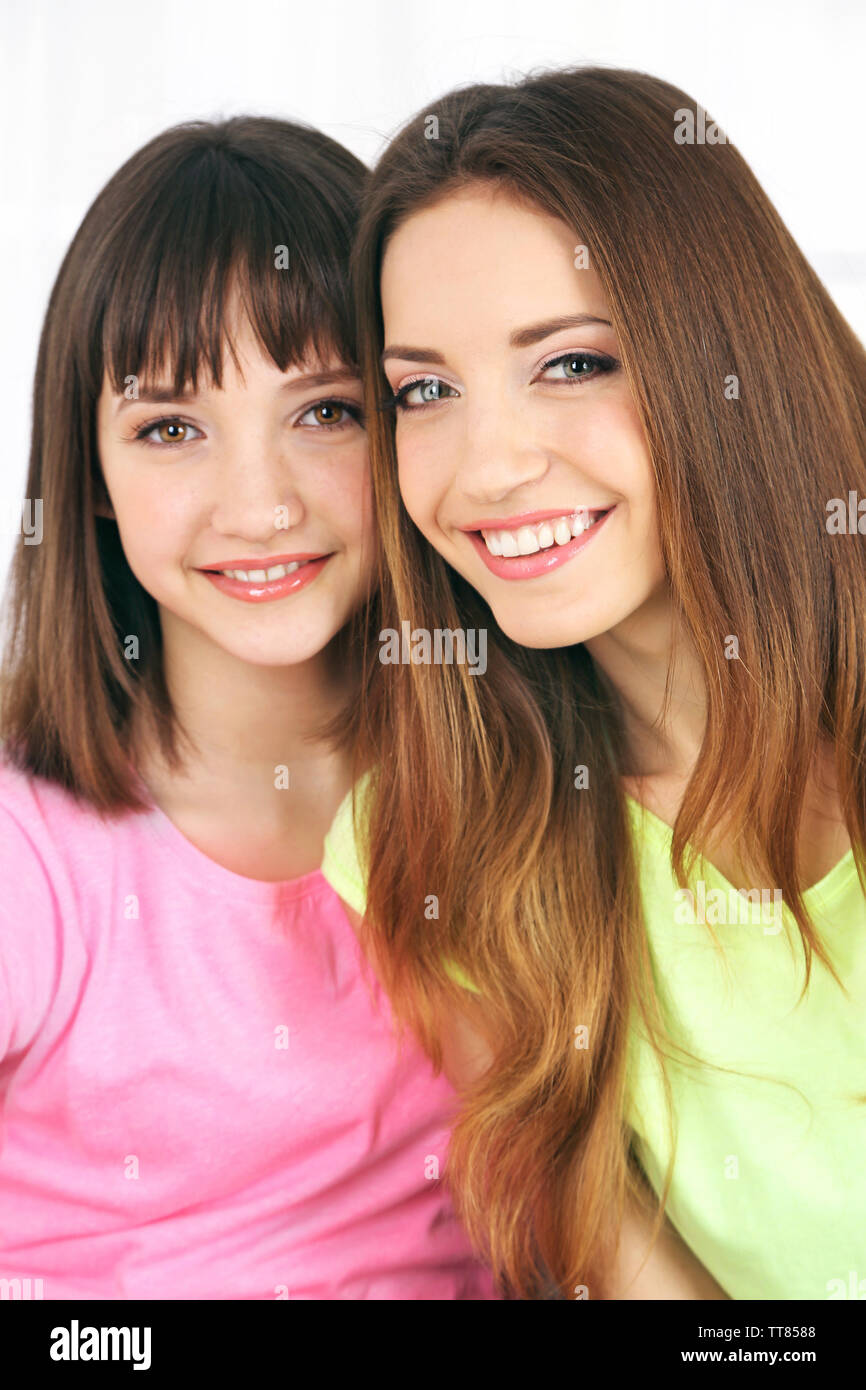 Two girls smiling on light background Stock Photo - Alamy
