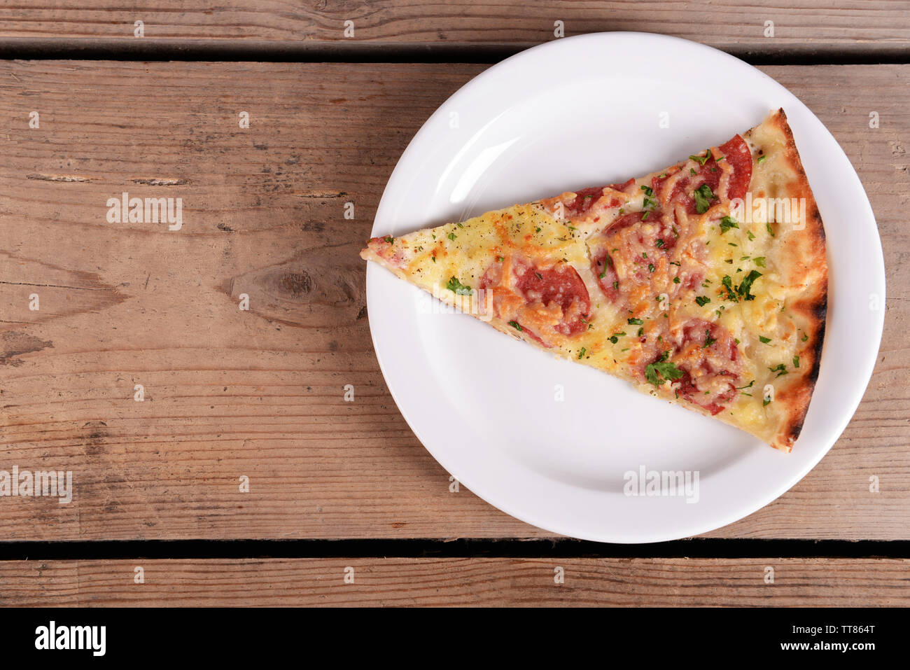 Tasty slice of pizza on plate on wooden table Stock Photo - Alamy