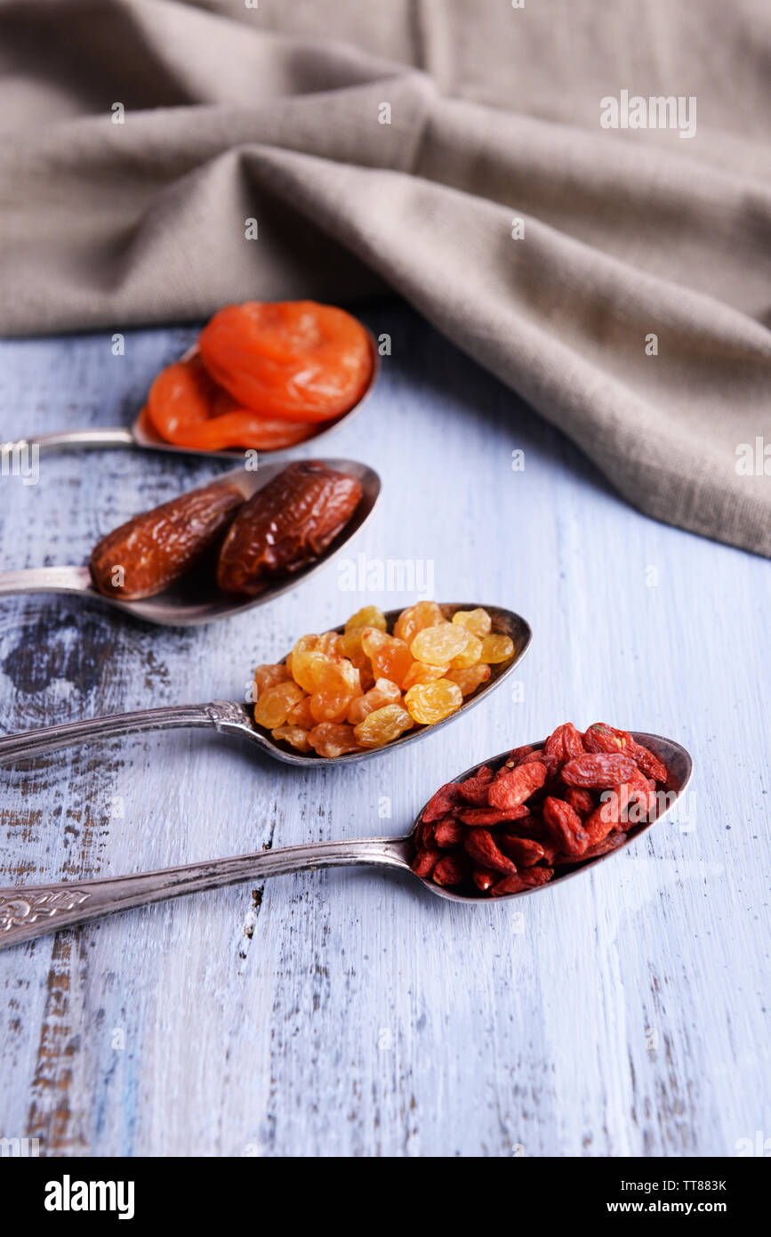 Dried fruits in silver spoons on color wooden table background Stock ...