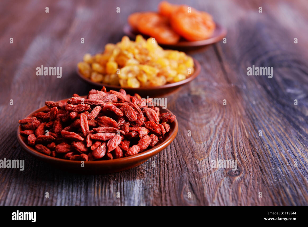 Dried fruits in small plates on rustic wooden table background Stock ...