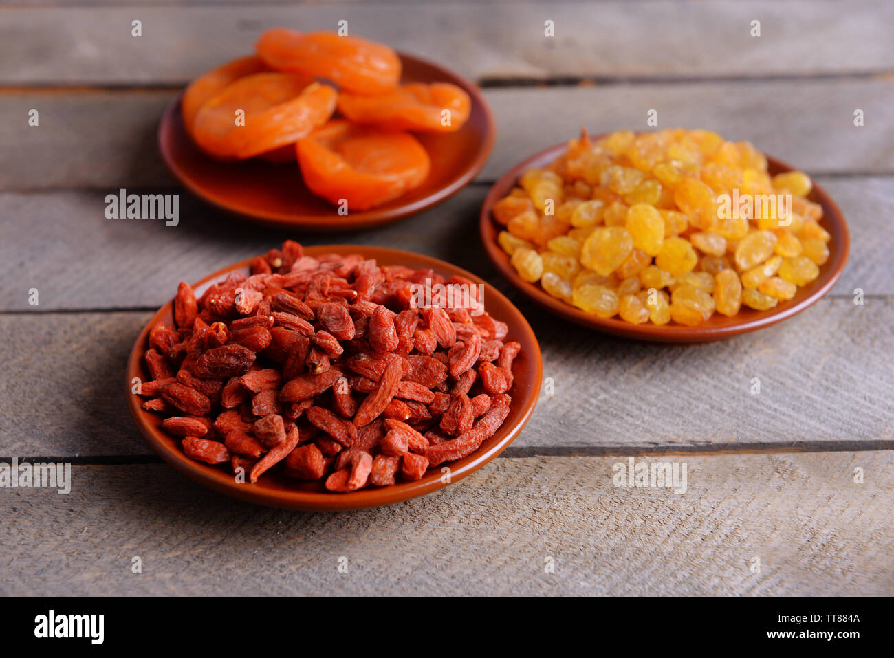 Dried fruits in small plates on wooden planks background Stock Photo ...