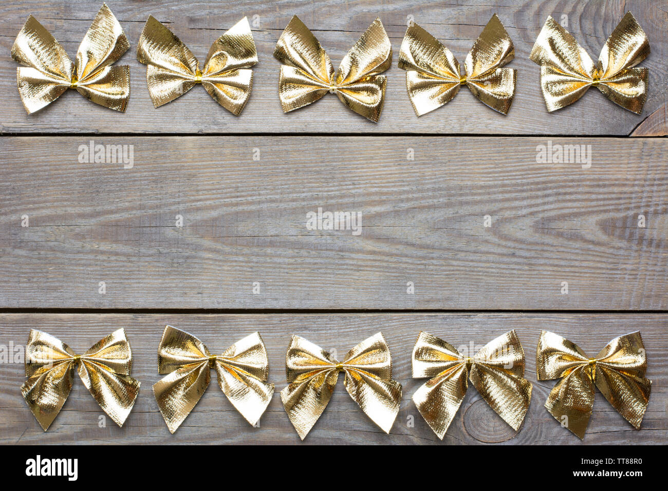 Two rows of golden bows on wooden background Stock Photo - Alamy