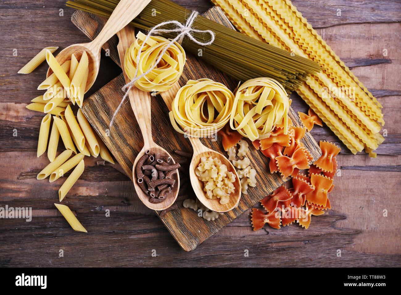 Different types of pasta on cutting board and wooden table background ...