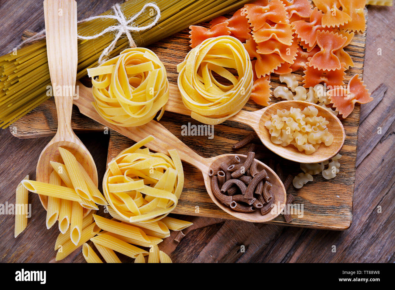 Different types of pasta on cutting board and wooden table background ...