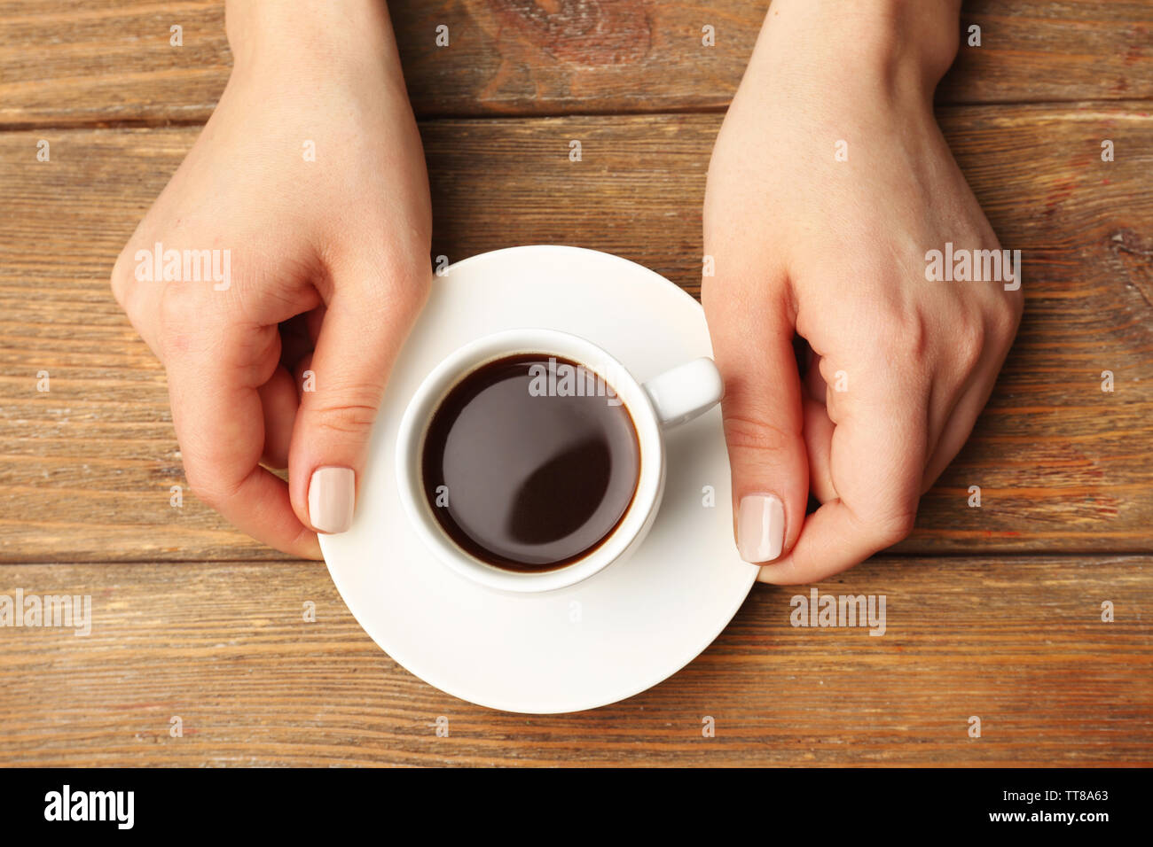 Female hands holding cup of coffee on wooden background Stock Photo - Alamy