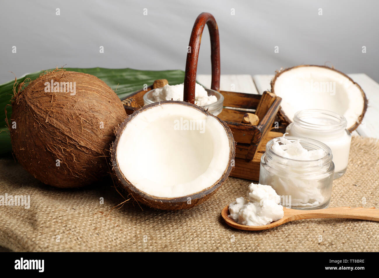 Coconut with jars of coconut oil and cosmetic cream on sackcloth on ...