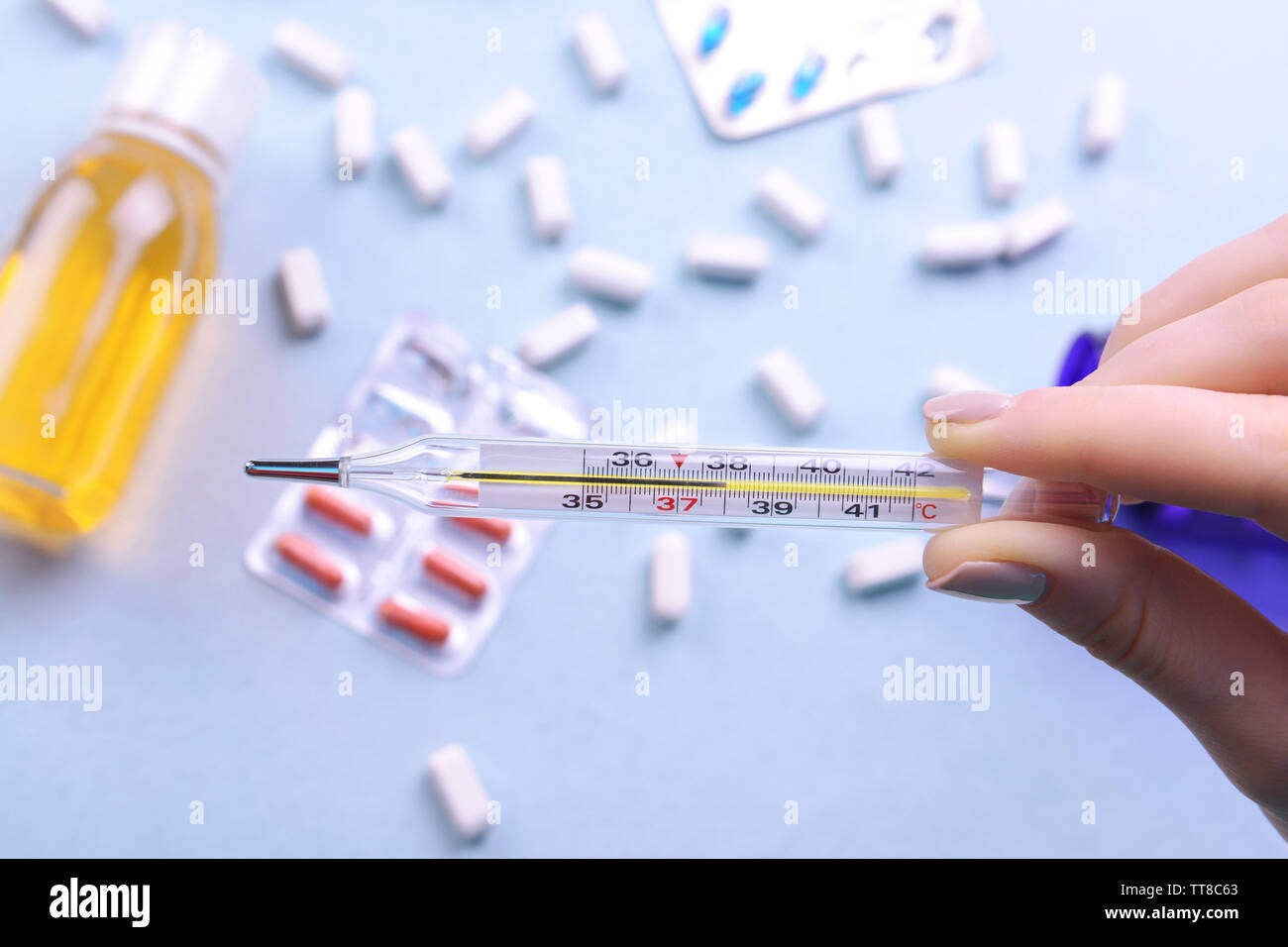 Hand holding thermometer on pills background Stock Photo - Alamy