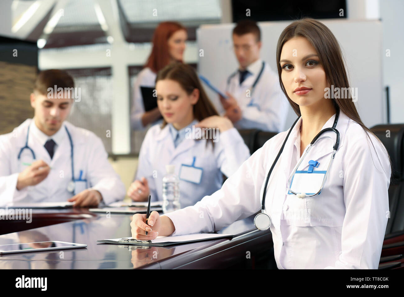 Beautiful young doctor with team in conference room Stock Photo - Alamy