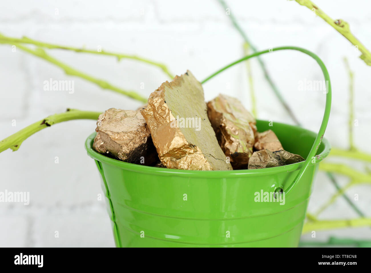 Gold in bucket on brick wall background Stock Photo - Alamy