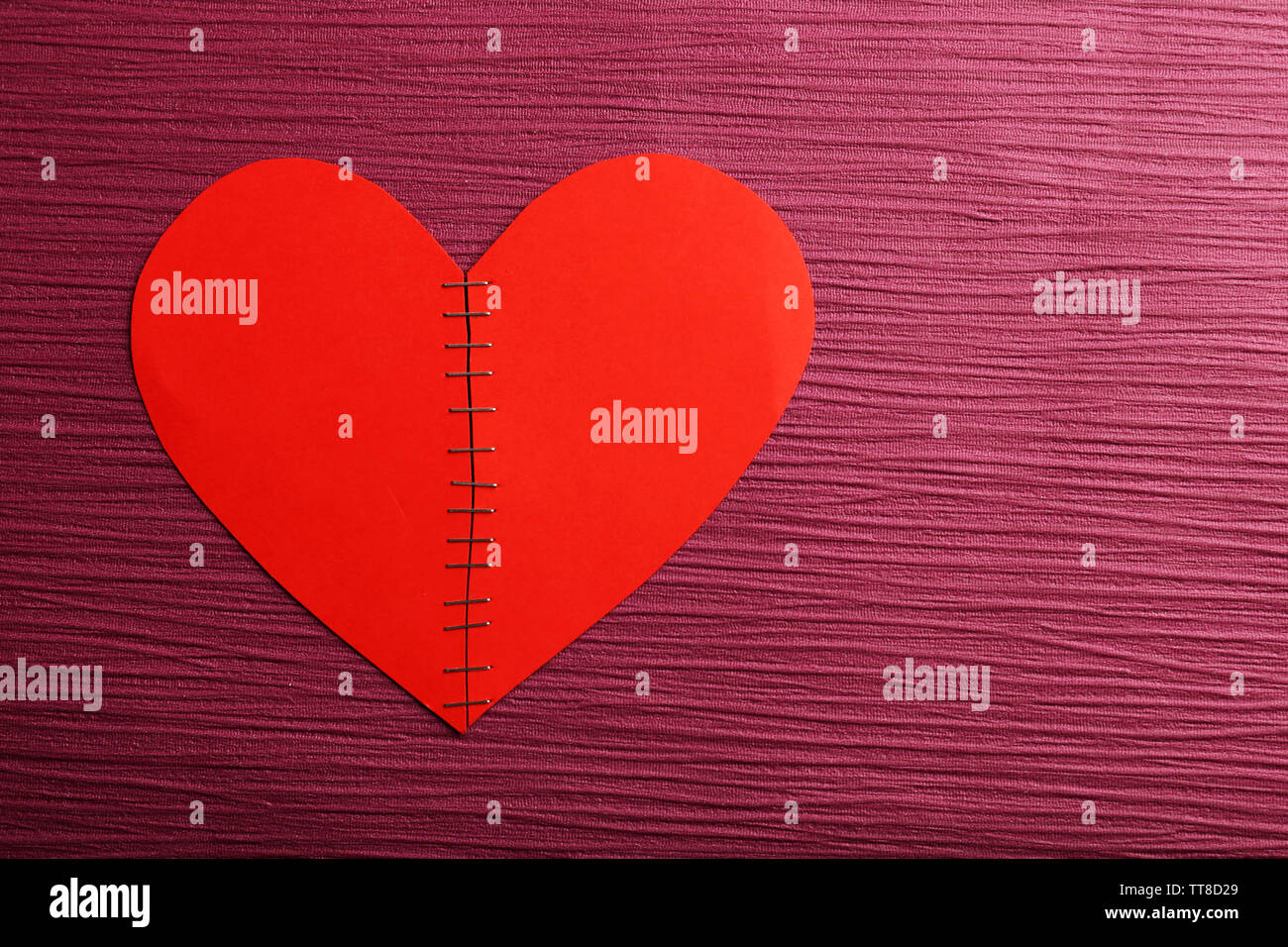 Broken heart stitched with staples on colour background Stock Photo - Alamy