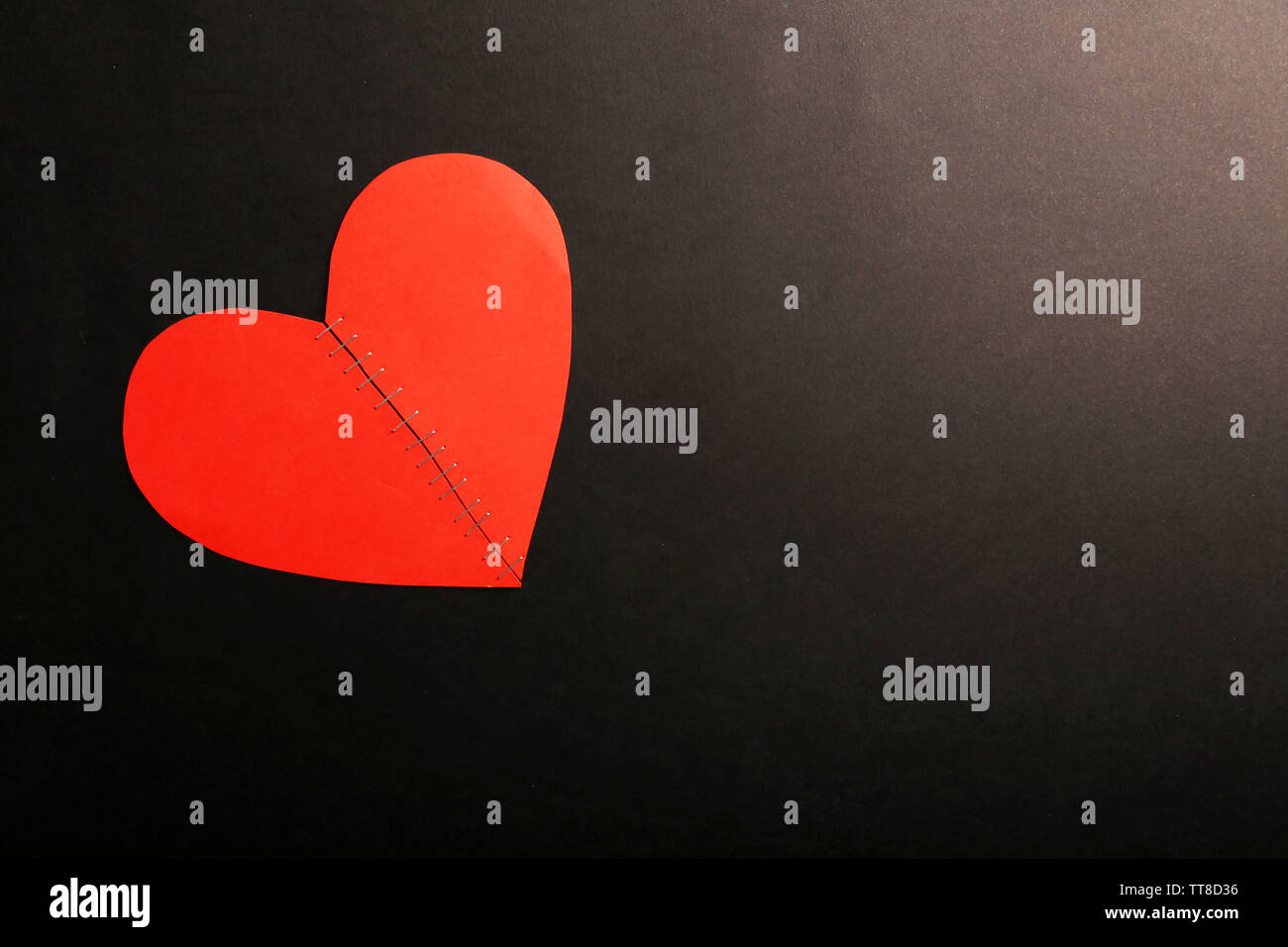Broken heart stitched with staples on black background Stock Photo - Alamy