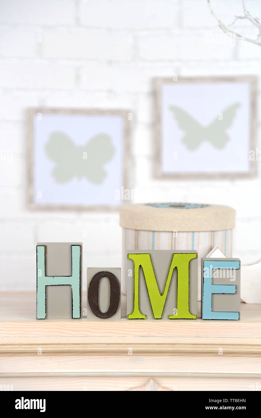 Home in colorful letters, in light white interior, on wooden shelf ...